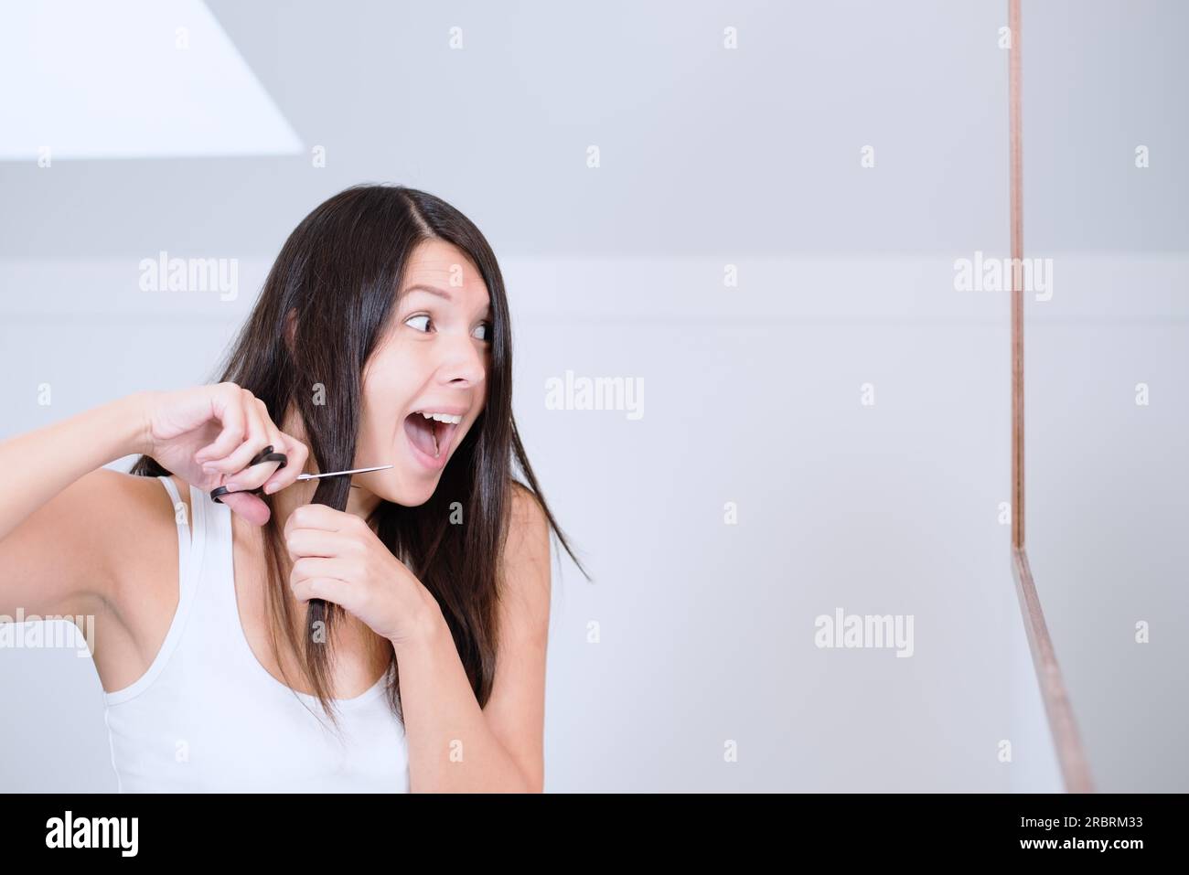 Attractive young woman with long brunette hair preparing to cut it with ...