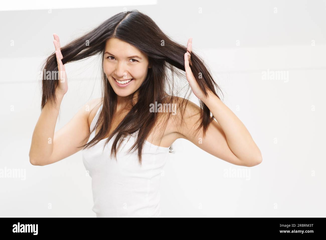 Joyful beautiful young woman playing with her long brunette hair ...