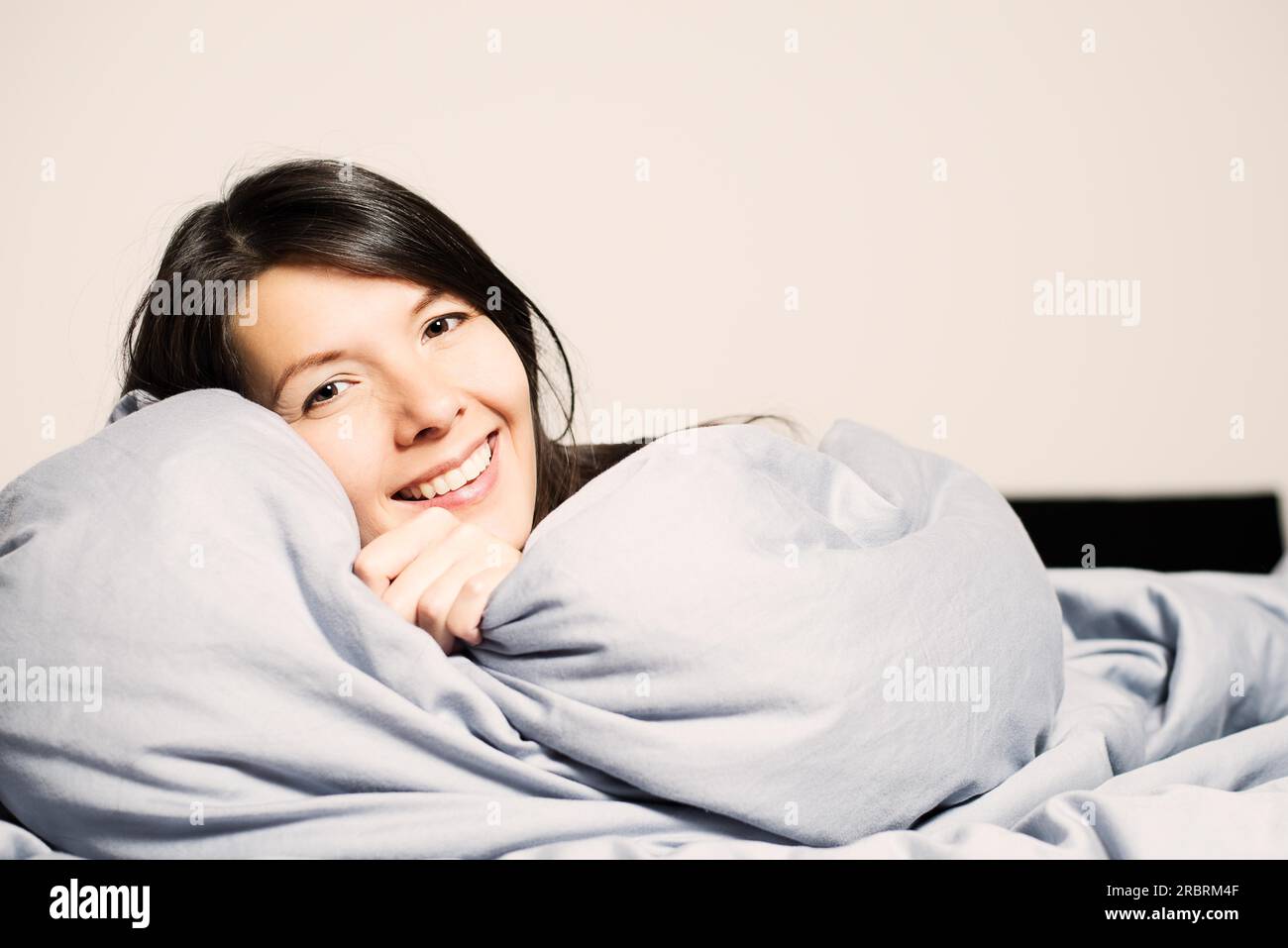 Laughing attractive young woman snuggling up in her comfortable warm ...