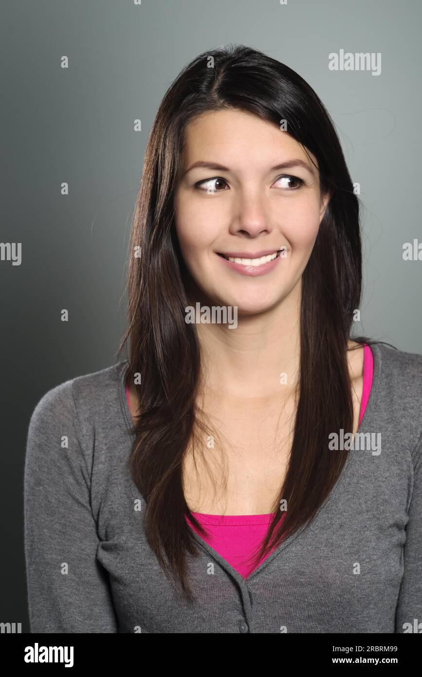 Attractive young woman with a lovely friendly smile glancing sideways ...