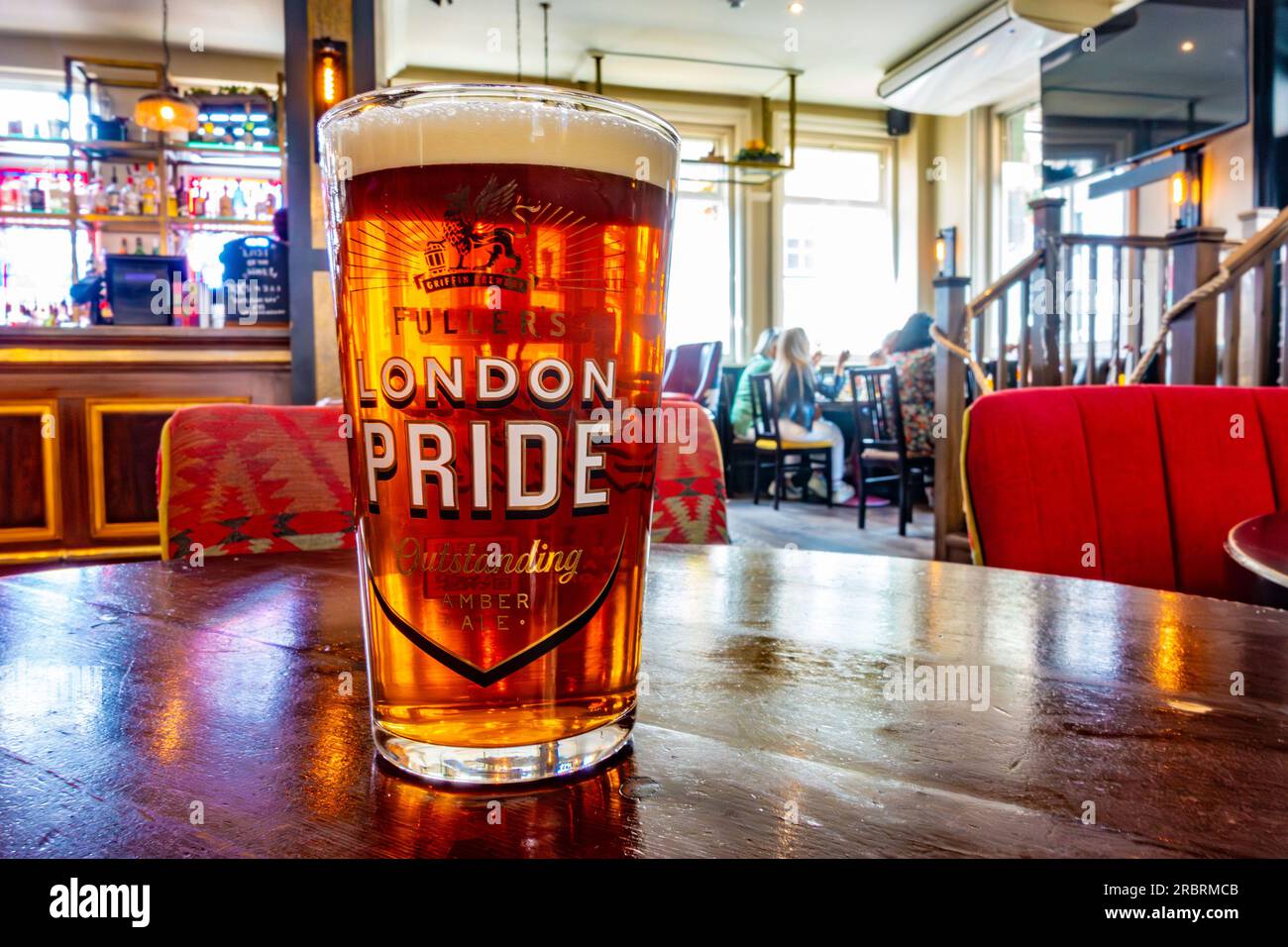 A pint of Fuller's London Pride beer on a wooden tabletop in a pub ...