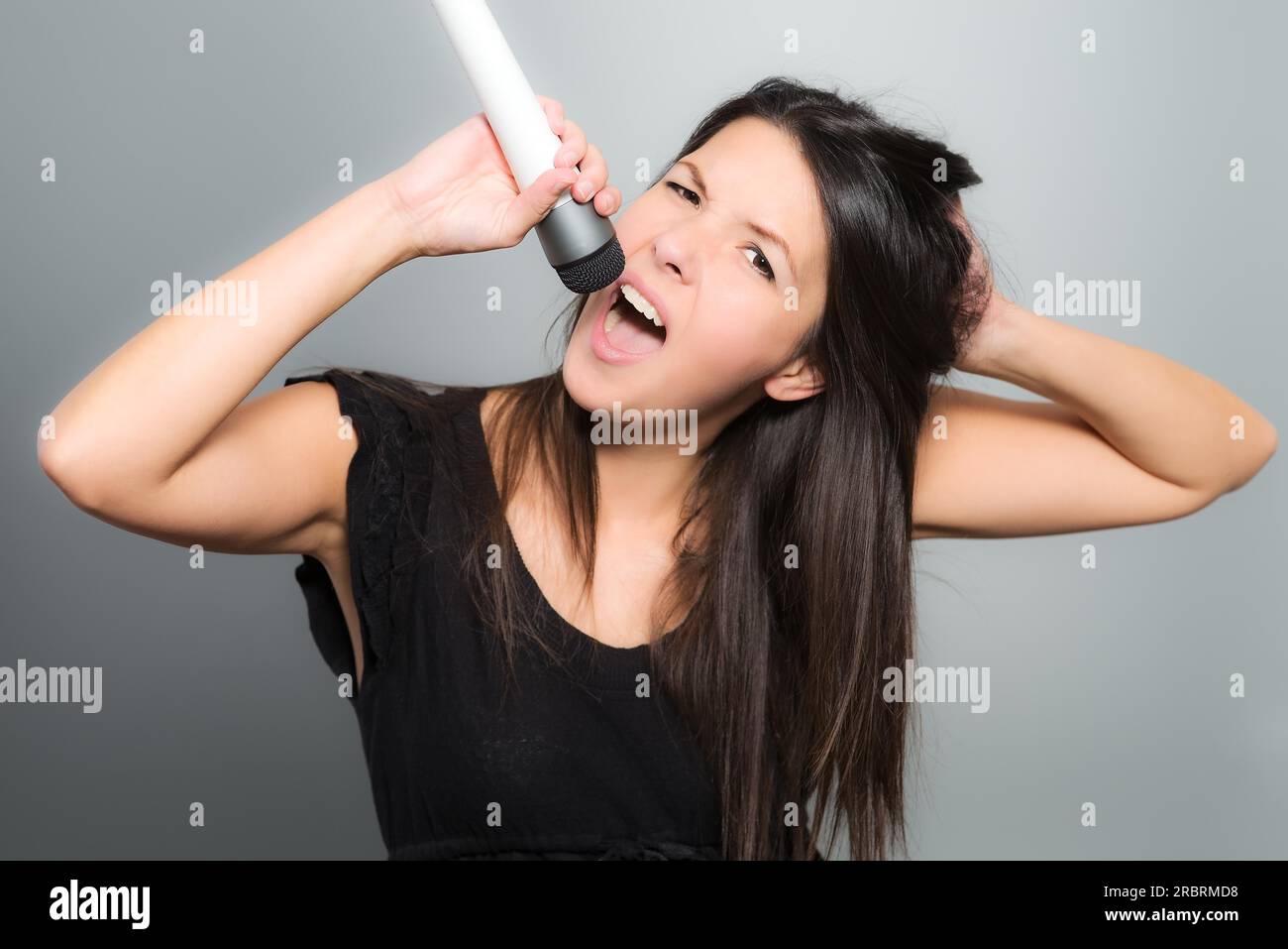 Emotional young woman singing her heart out into a microphone as she ...