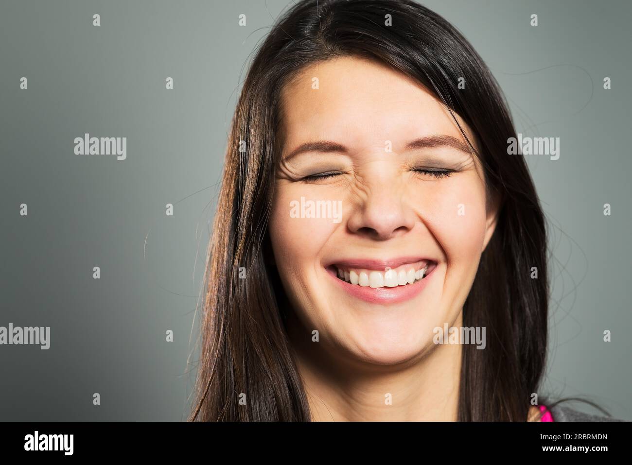 Happy pleased woman with a beaming toothy smile with her eyes closed ...