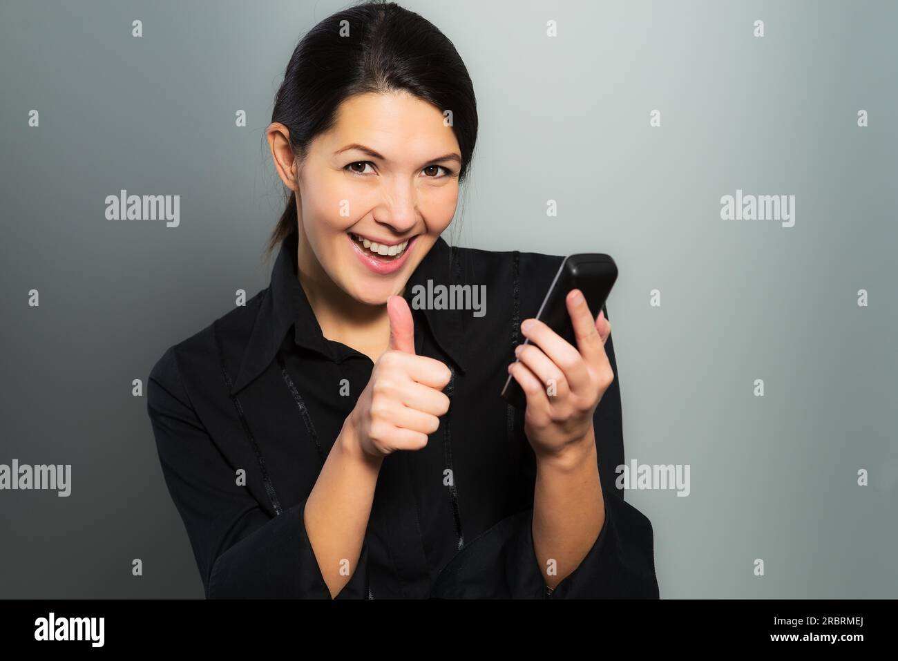 Beautiful young woman cheering and giving a thumbs up in jubilation at ...