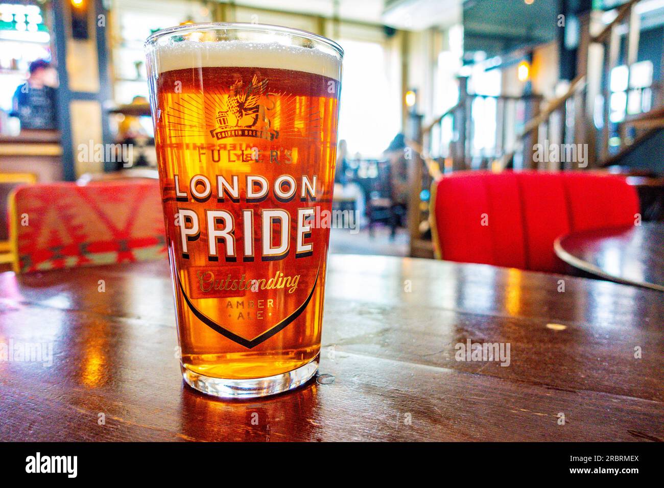 A pint of Fuller's London Pride beer on a wooden tabletop in a pub ...