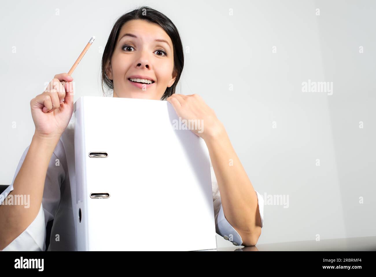 Creative intelligent young woman pointing up with the pencil while ...