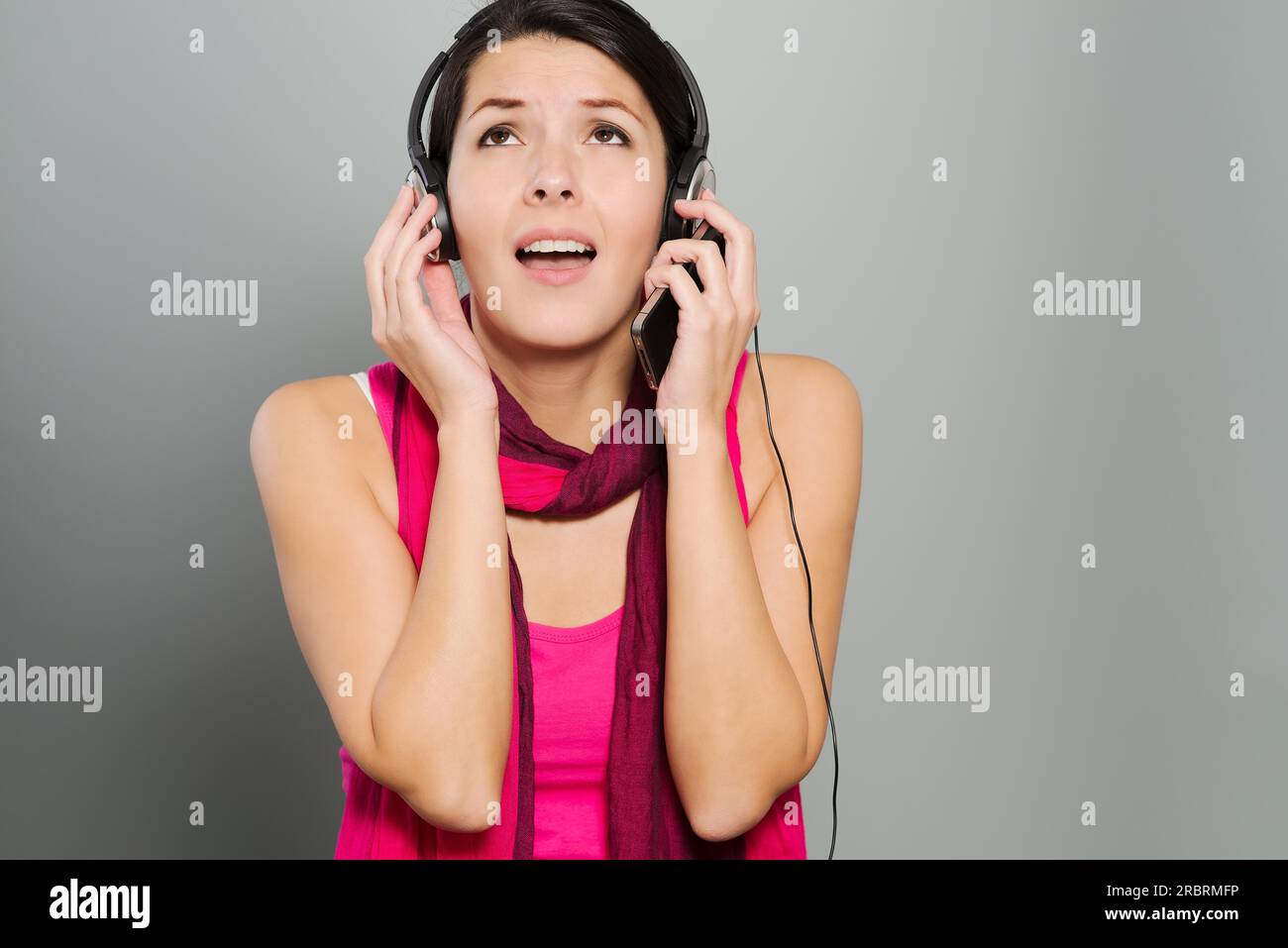 Beautiful vivacious woman listening to music on headphones connected to ...