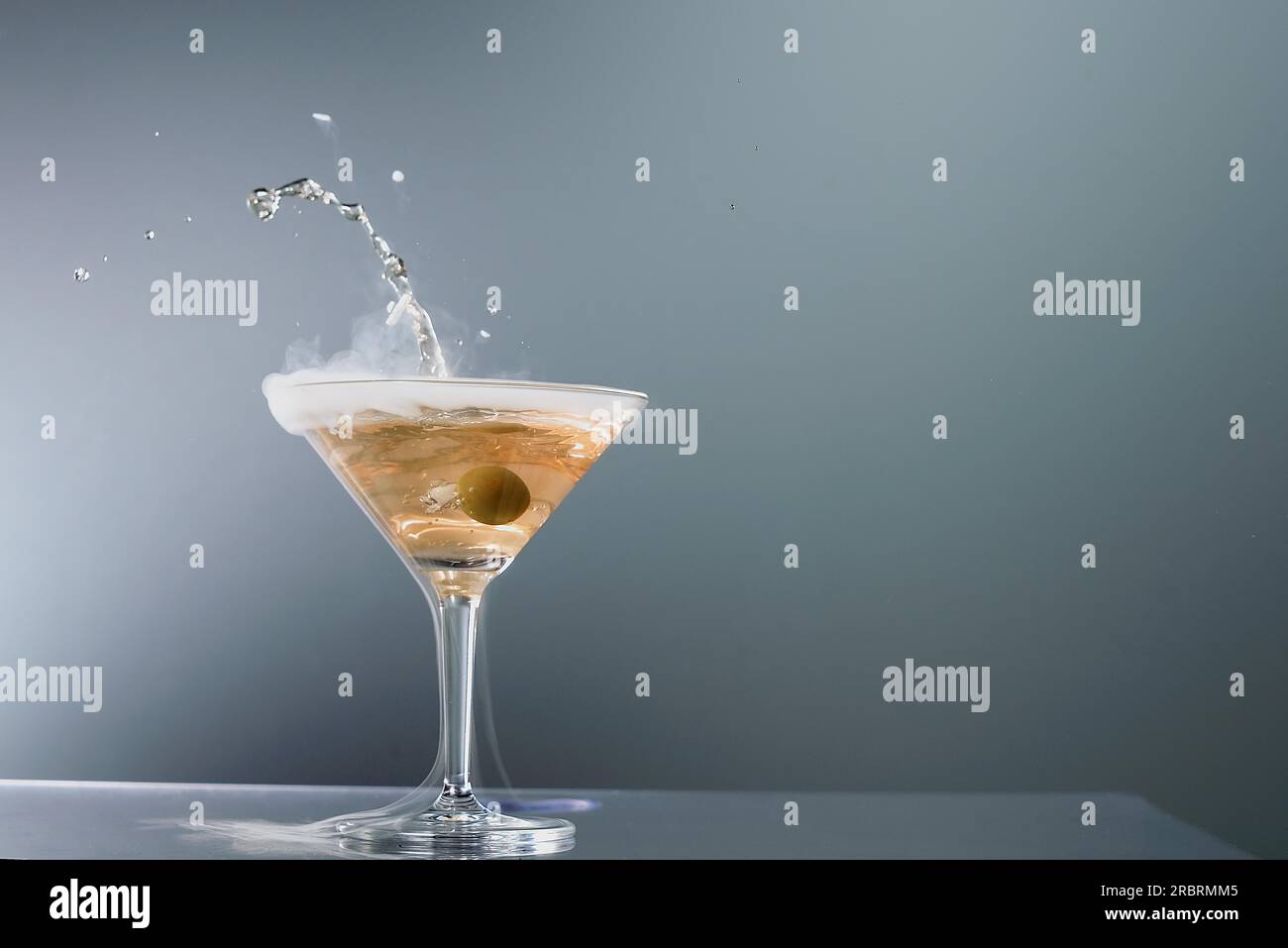 Smoking martini cocktail in a conical glass with wafting vapour and ...