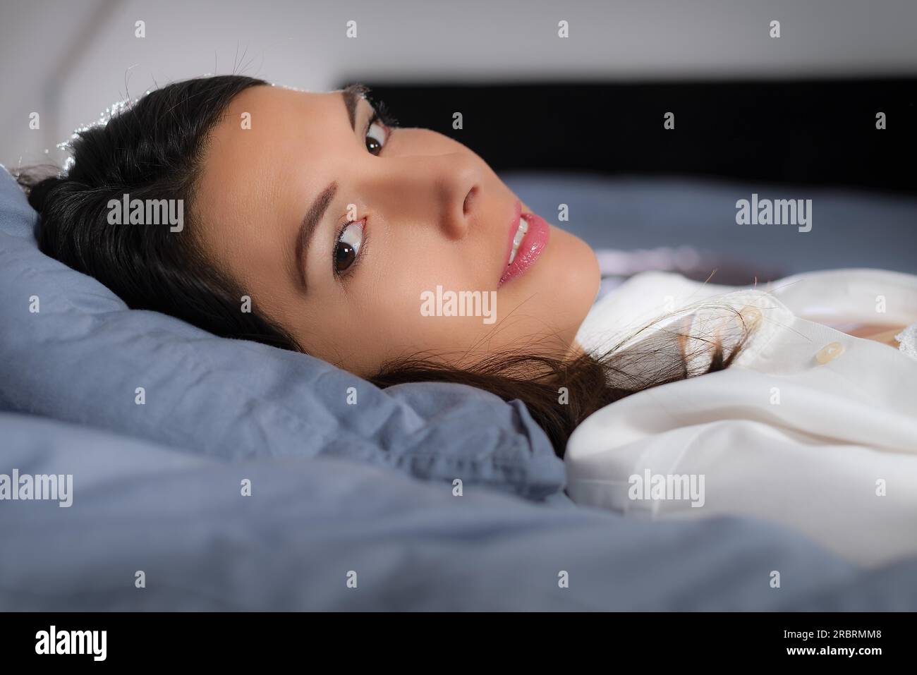 Low angle closeup view of a refreshed young woman resting in bed lying ...