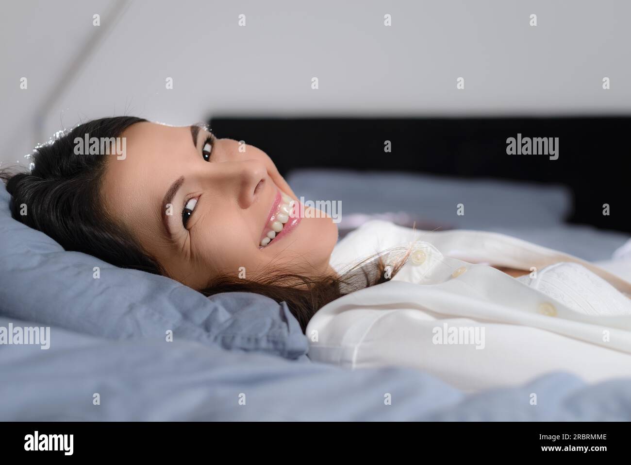 Low angle closeup view of a refreshed happy young woman resting in bed ...