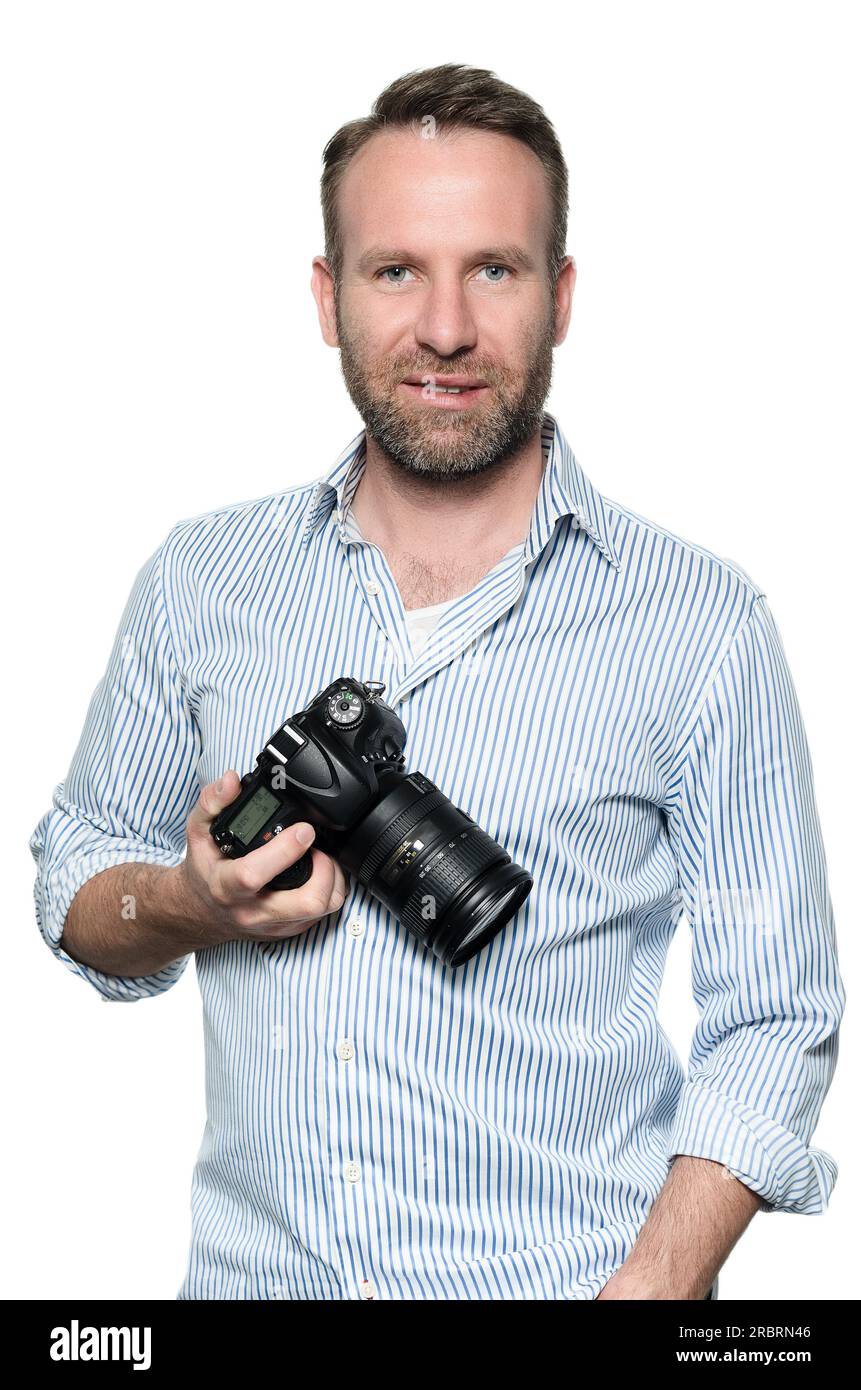 Handsome photographer with a friendly smile standing holding his camera ...