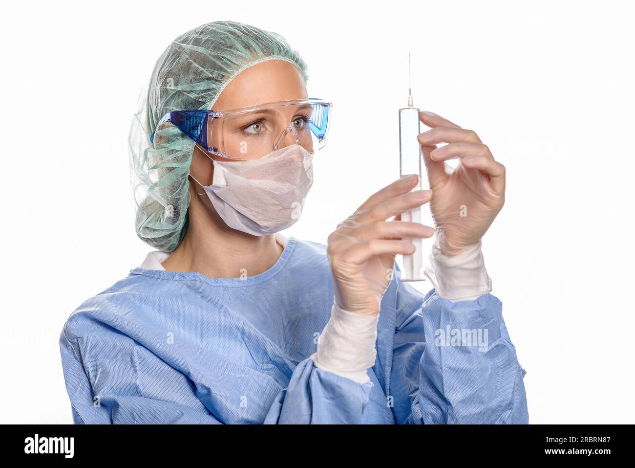 Female doctor or nurse in a gown, goggles, cap, and mask ready to give ...