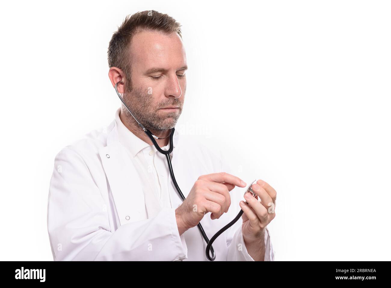 Smiling unshaven male doctor testing a stethoscope in his hand ready to ...