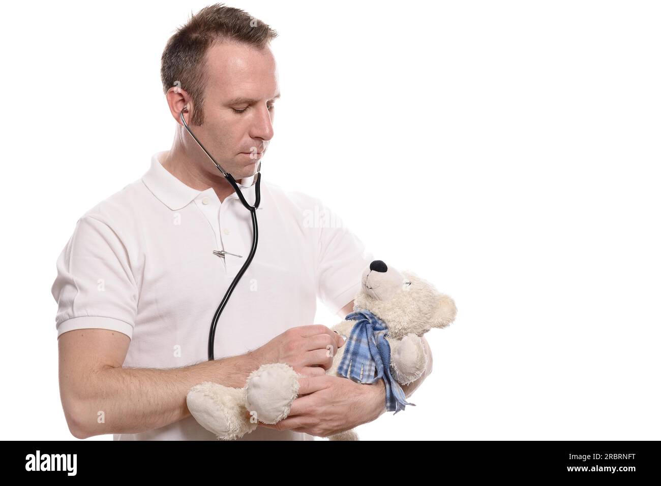 Pediatrician listening to a teddy bears heart using his stethoscope ...