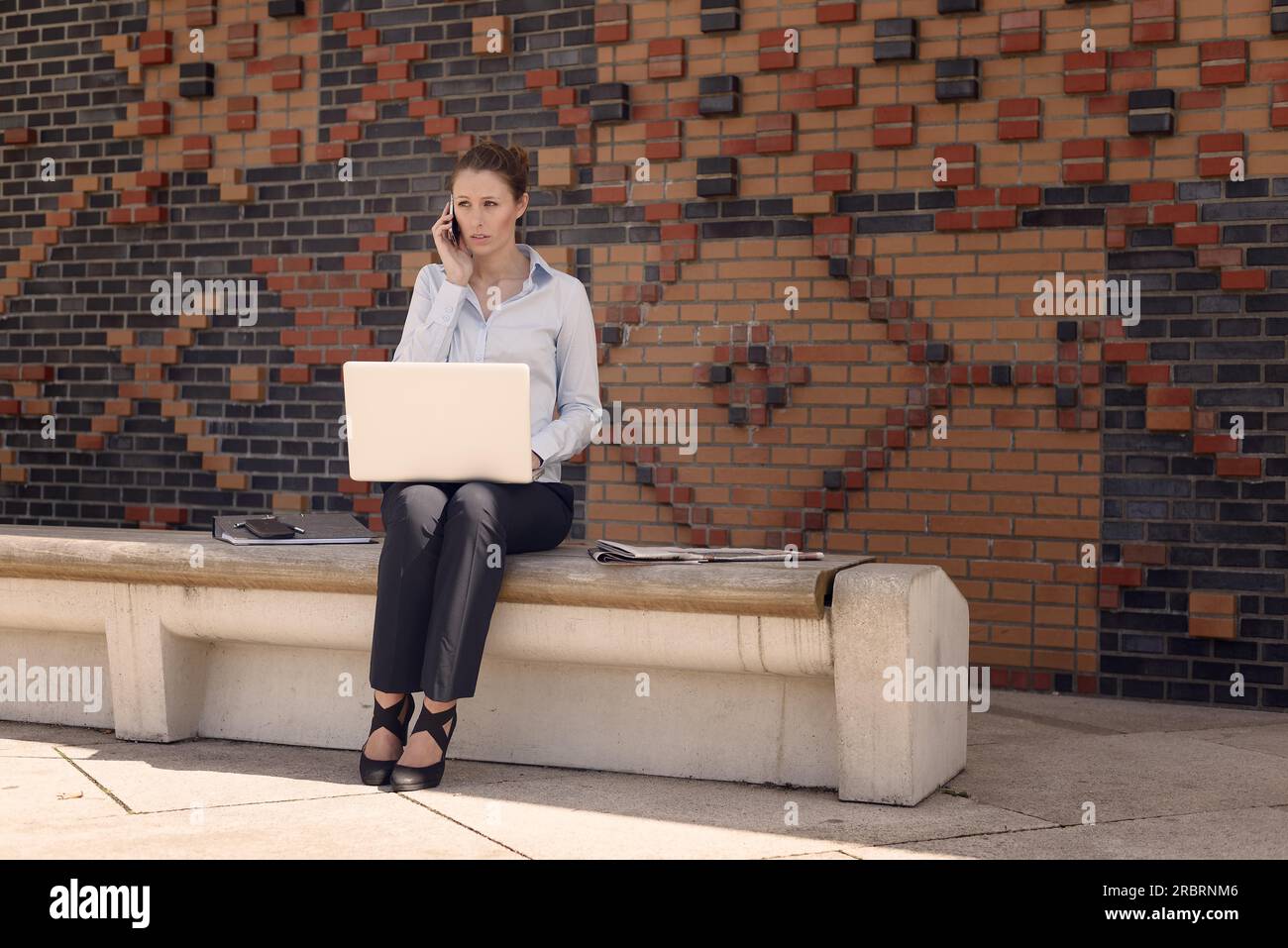 Friendly attractive young woman sitting talking on a mobile phone while ...