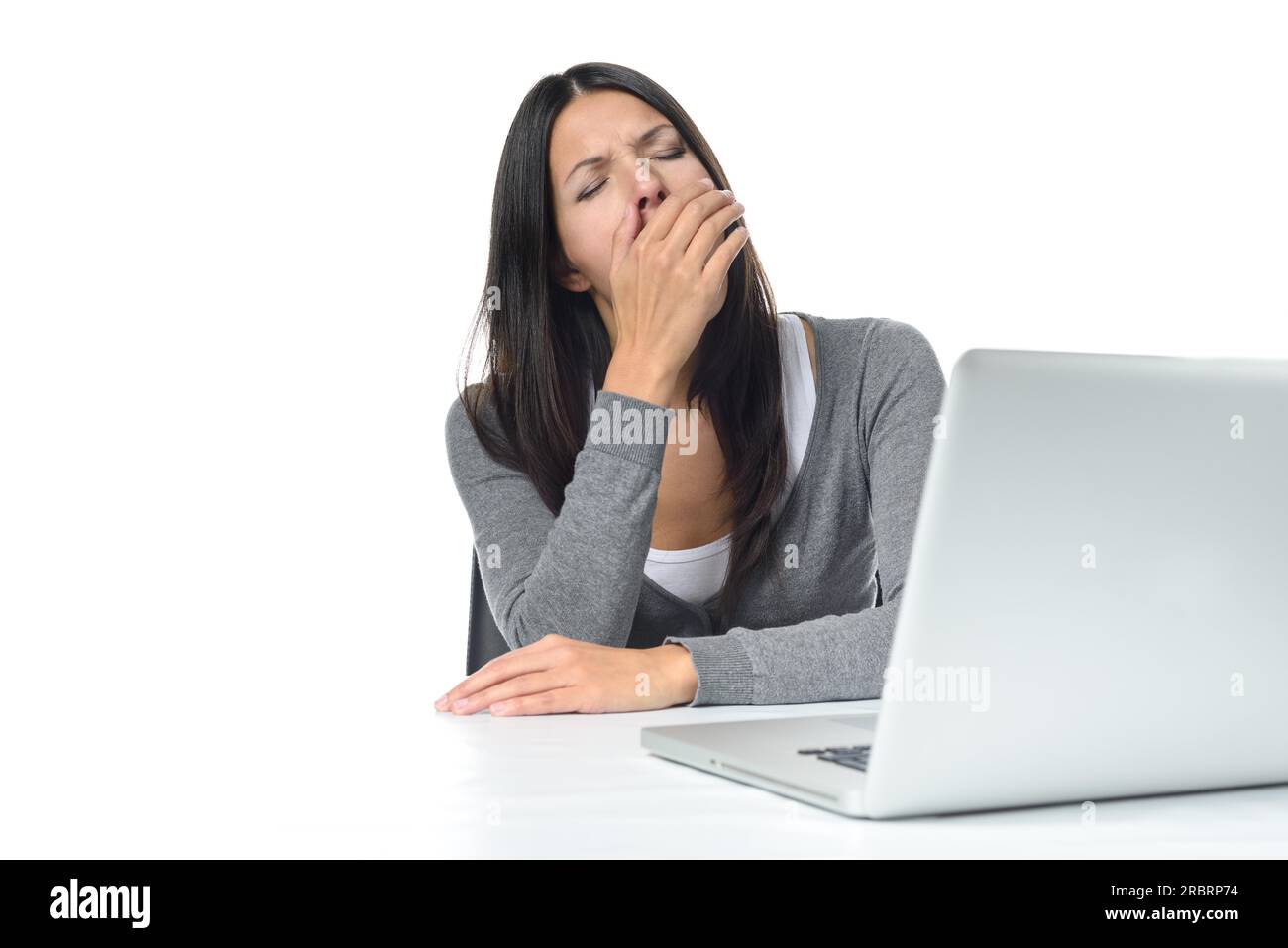 Tired young businesswoman yawning after a long days work as she winds ...