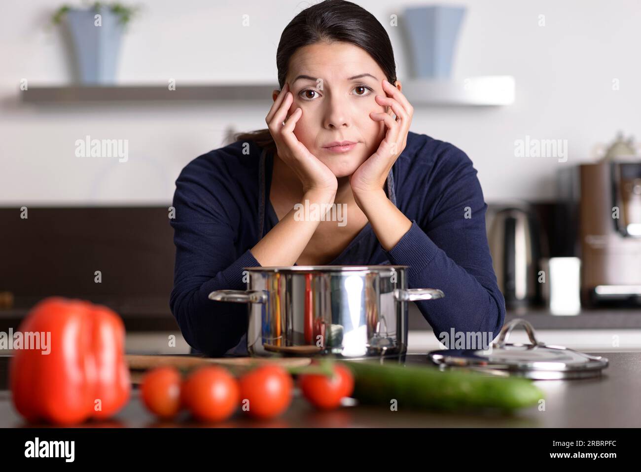 Unmotivated attractive young woman preparing the dinner leaning on the ...
