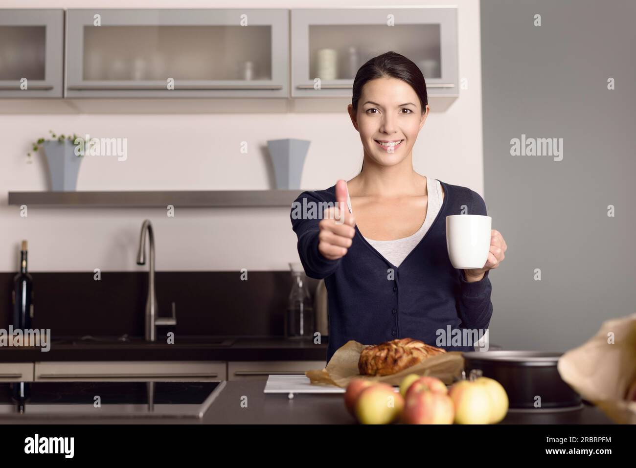 Happy attractive young female cook giving a thumbs up of approval and ...