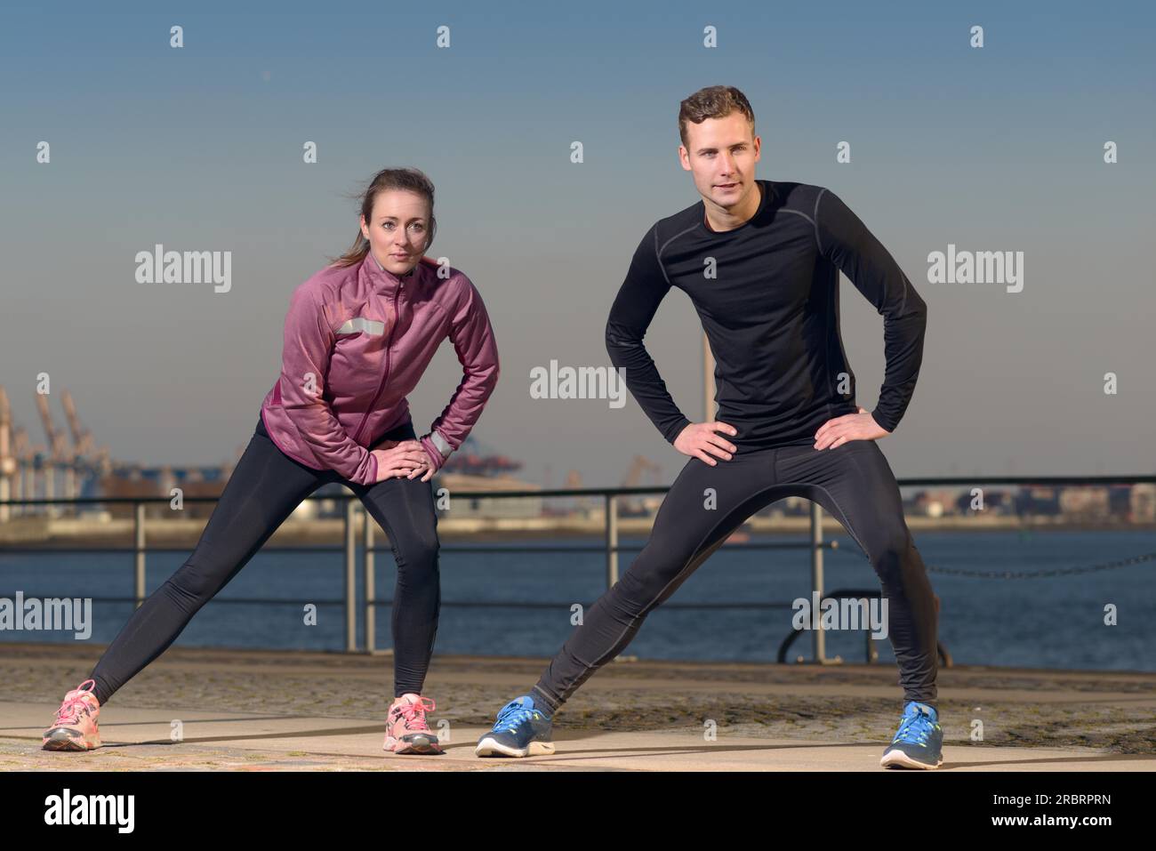 Young couple exercising at the waterfront standing on the esplanade in ...