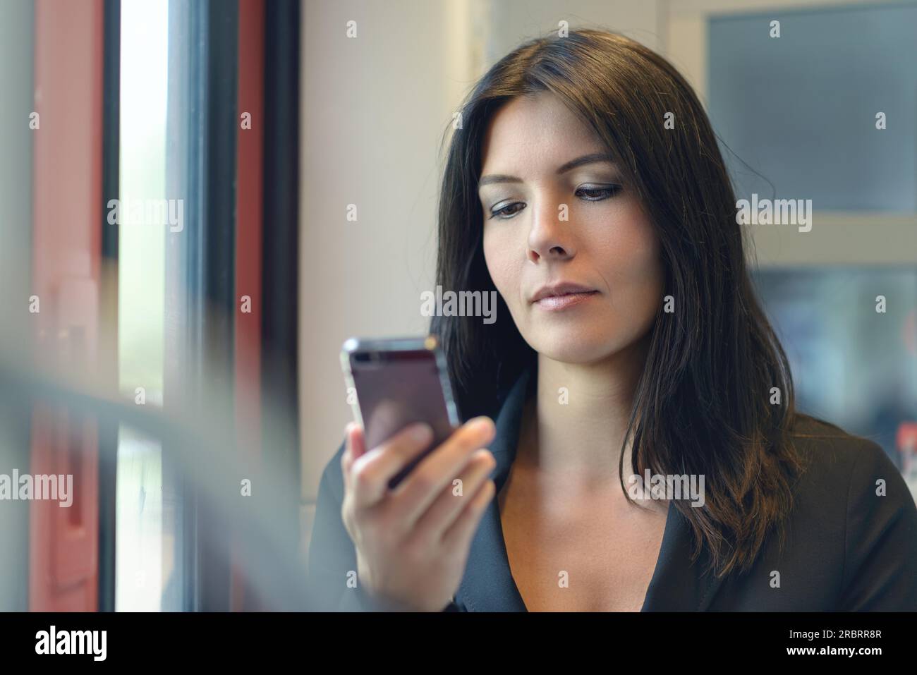 Woman reading a text message on her mobile phone with a serious ...