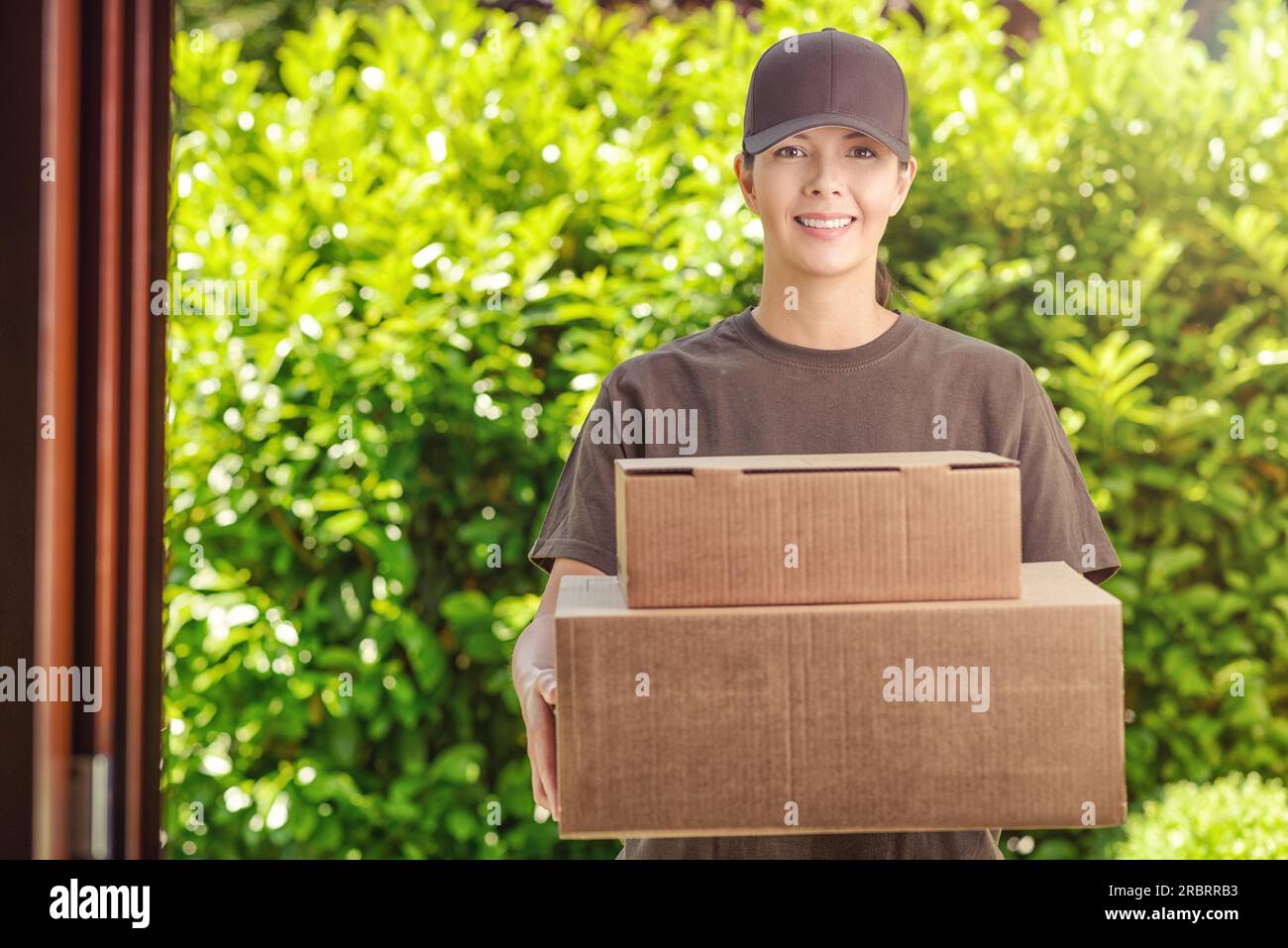 Attractive delivery woman or courier with two cardboard boxes in her ...