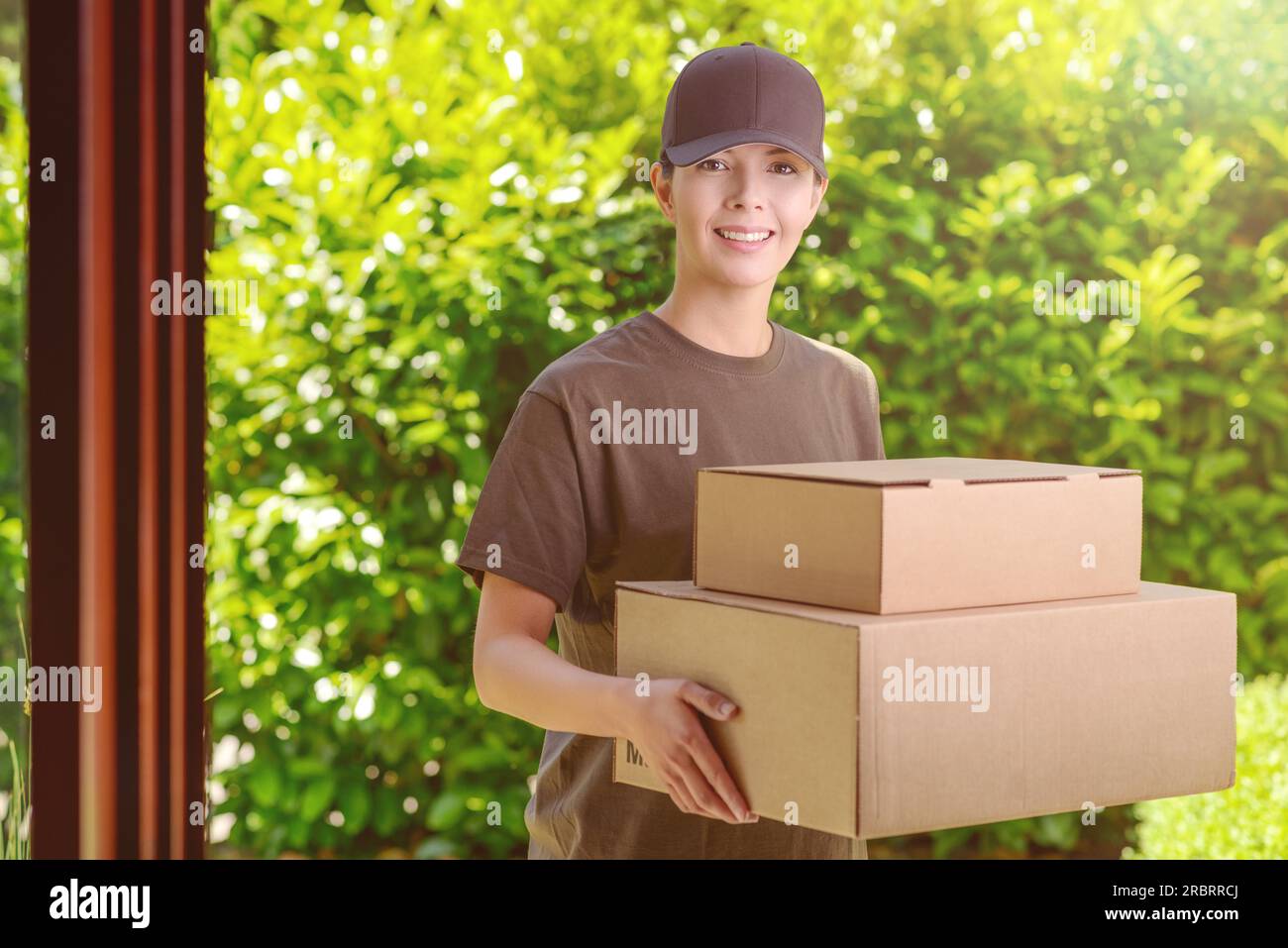 Attractive delivery woman or courier with two cardboard boxes in her ...