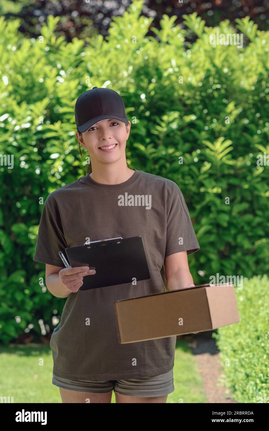 Smiling attractive female courier in a cap delivering a parcel to the ...