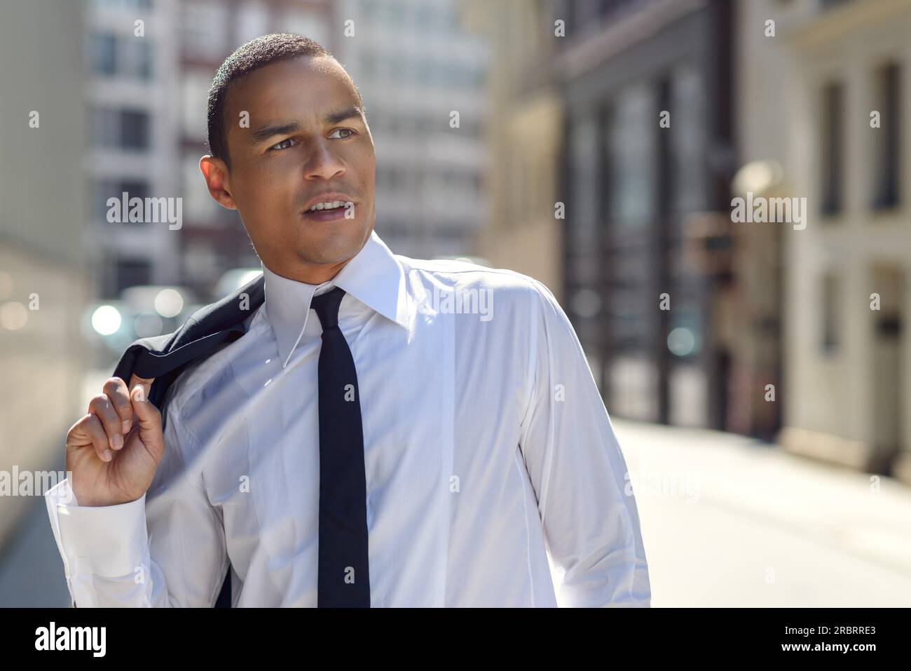 Handsome businessman walking in an urban street with his suit jacket ...