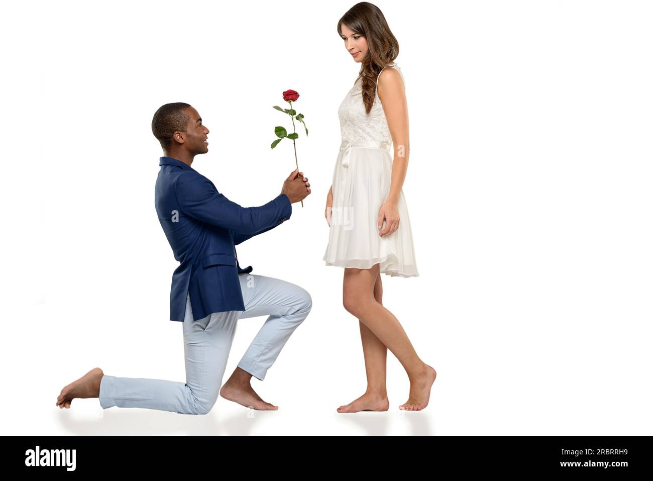 Romantic hipster barefoot young man kneeling on the floor proposing to ...