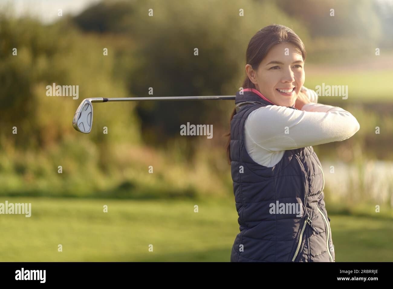 Smiling friendly young woman golfer looking at the camera after ...