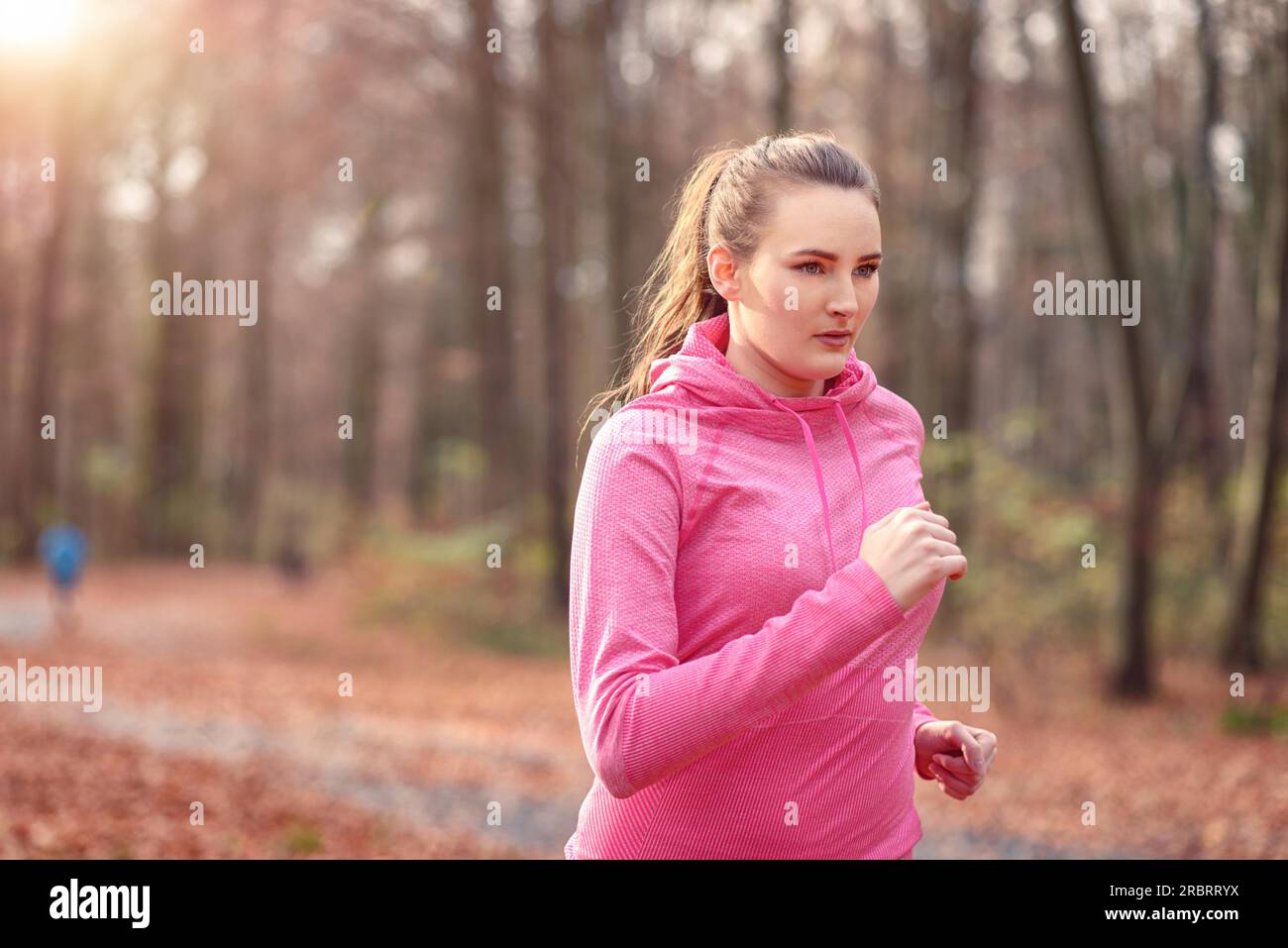 Pretty fit young woman jogging through autumn or fall woodland ...