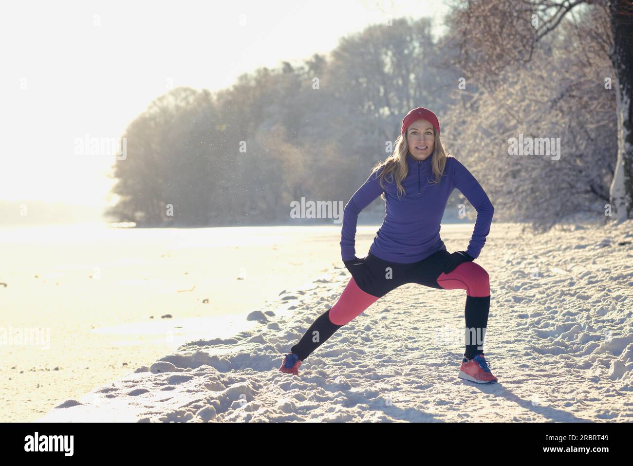 Active young woman exercising outdoors in a park in fresh white winter ...