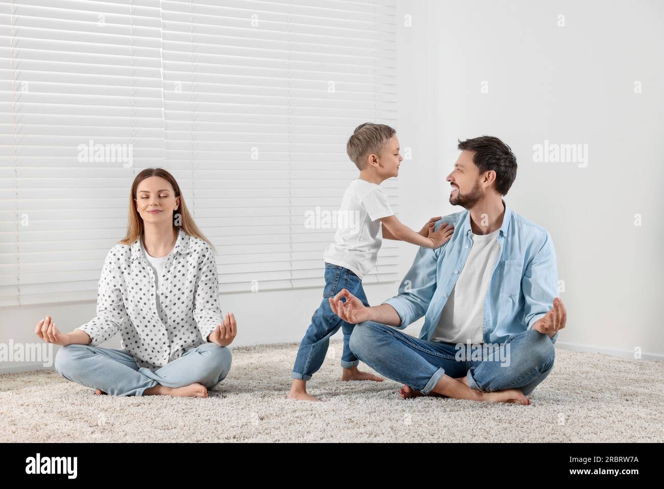 Parents meditating while son distracting them at home Stock Photo - Alamy