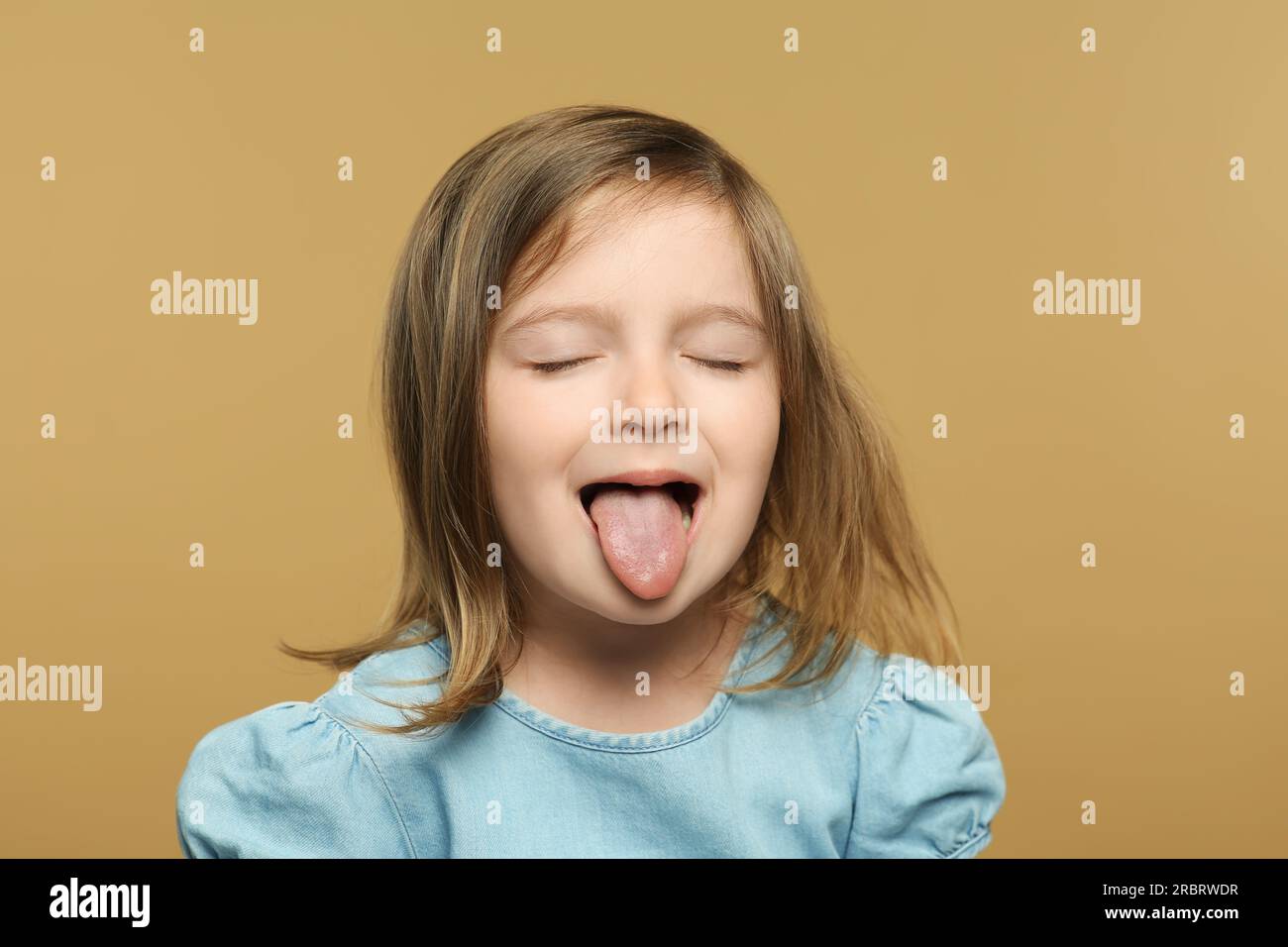 Funny little girl showing her tongue on beige background Stock Photo ...