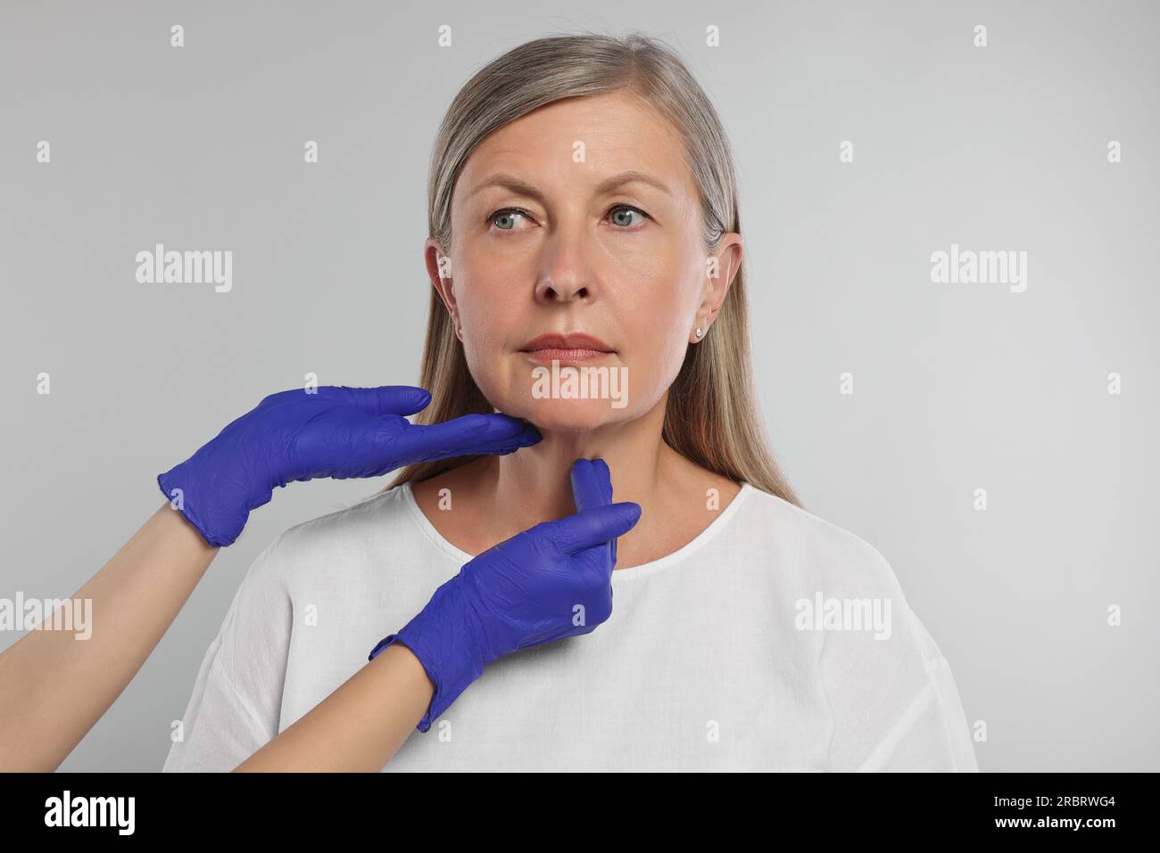 Endocrinologist examining thyroid gland of patient on light grey ...