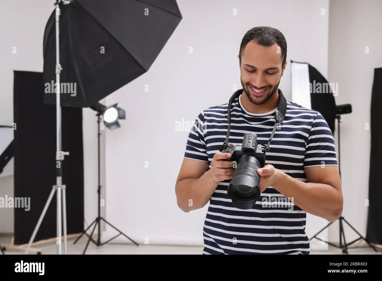 Young professional photographer with camera in modern photo studio ...