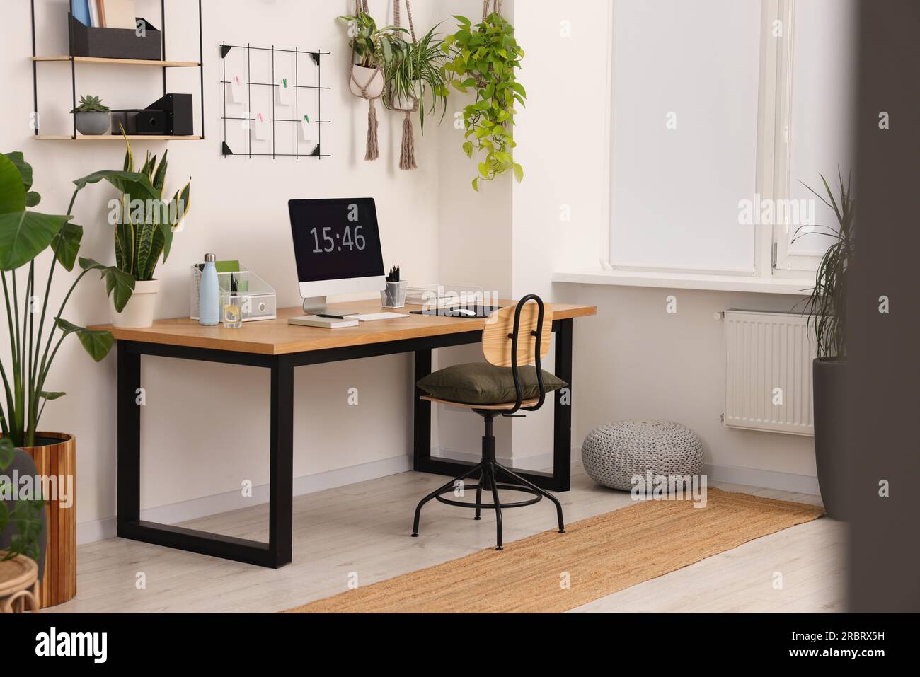 Cozy workplace with computer, modern furniture and houseplants at home ...