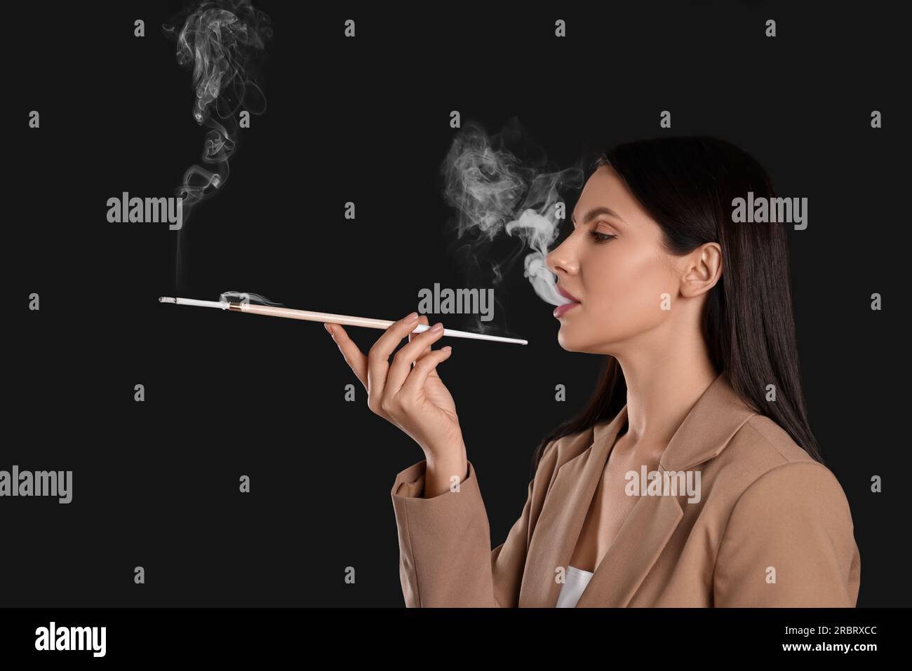 Woman using long cigarette holder for smoking on black background Stock ...