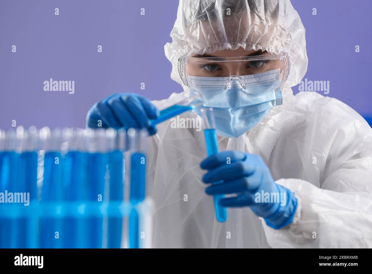 Scientist holding test tubes with light blue liquids in laboratory ...