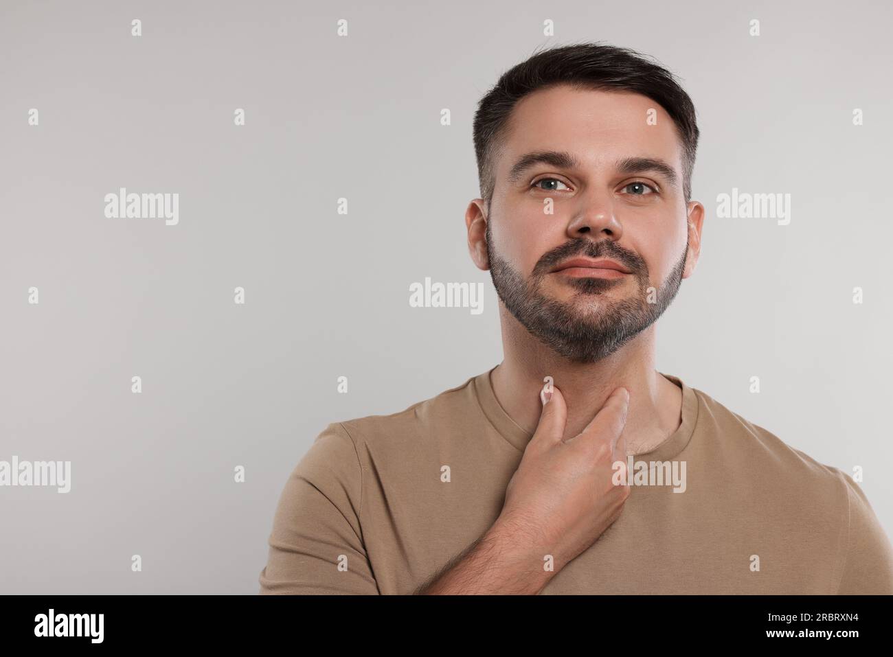 Endocrine system. Man doing thyroid self examination on light grey ...