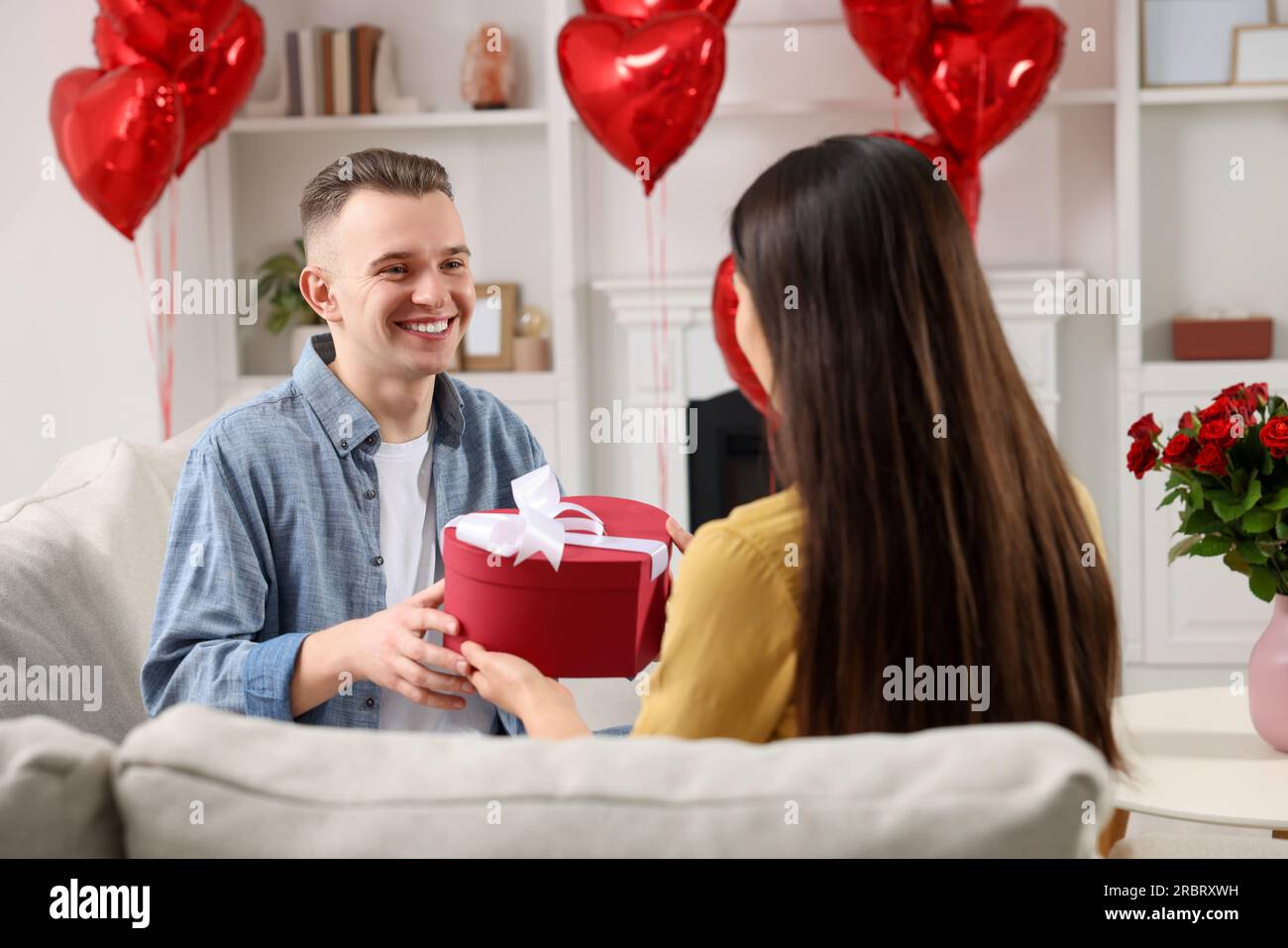 Man receiving gift box from his girlfriend at home. Valentine's day ...
