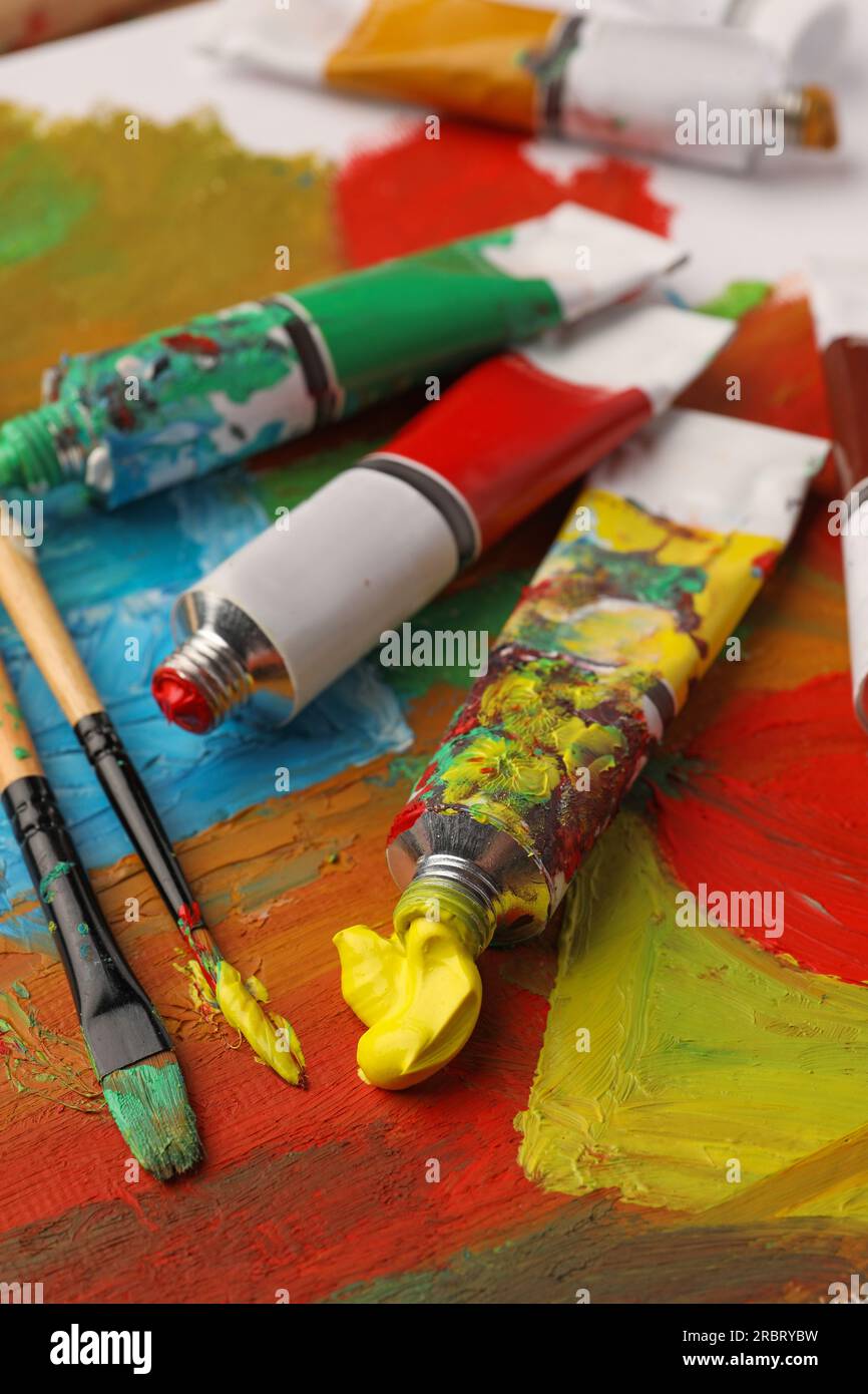 Tubes of colorful oil paints and brushes on canvas with abstract ...