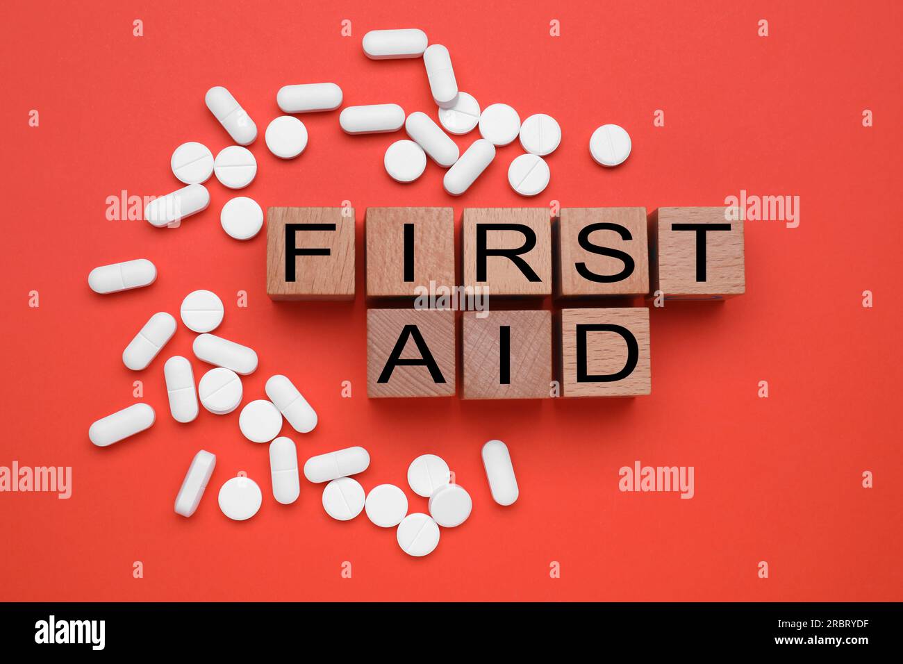 Words First Aid made of wooden cubes and pills on coral background ...
