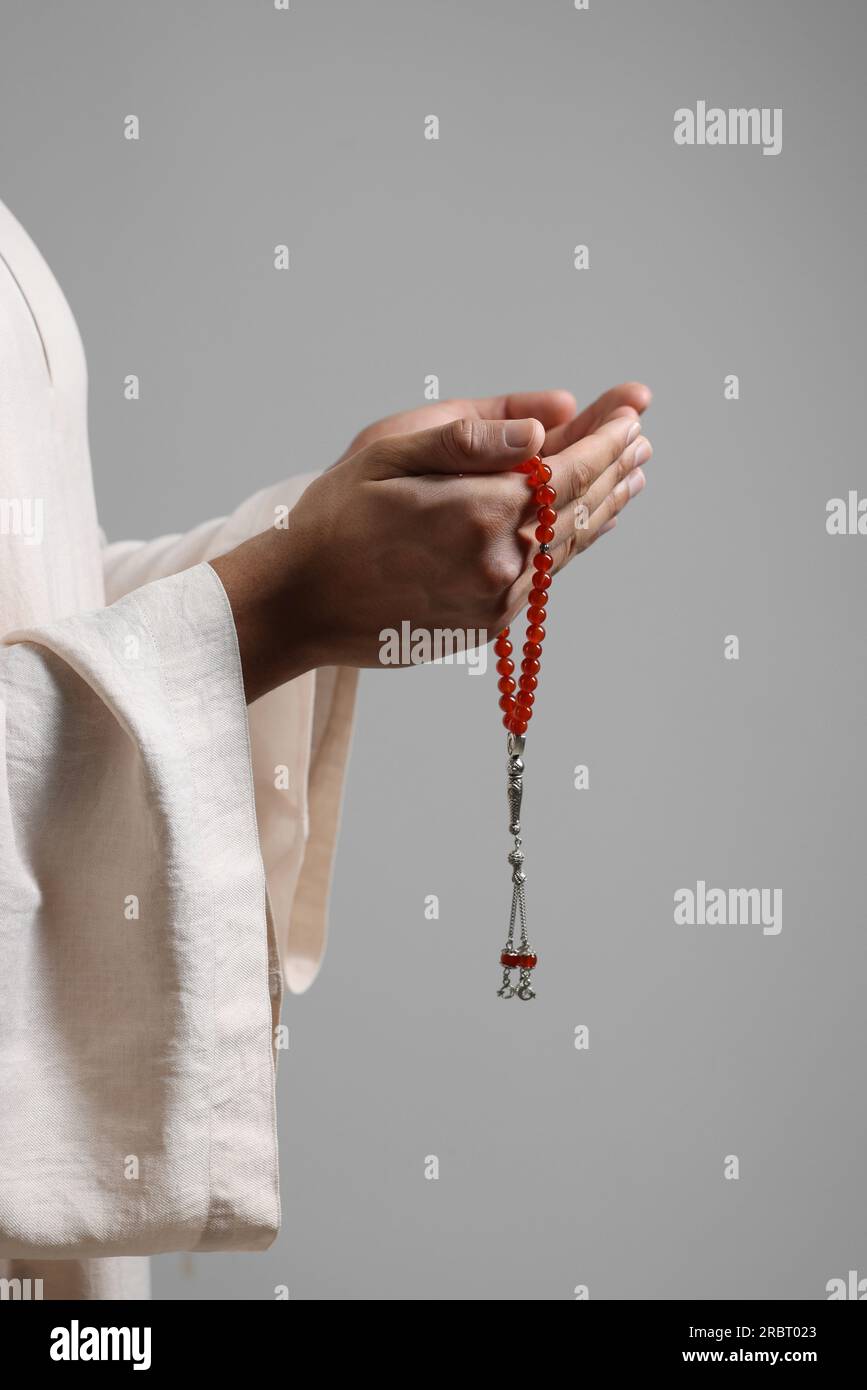 Muslim man with misbaha praying on light grey background, closeup Stock ...