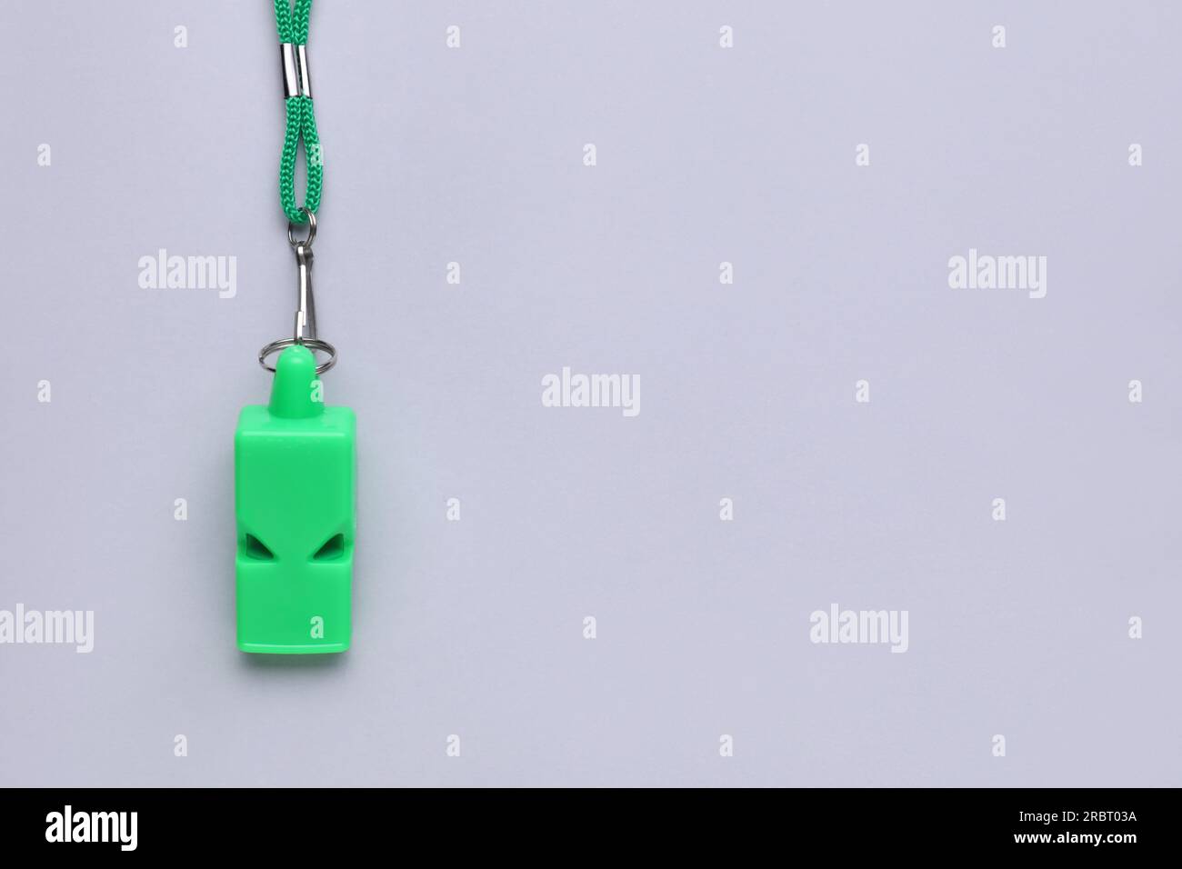 One green whistle with cord on light grey background, top view. Space ...