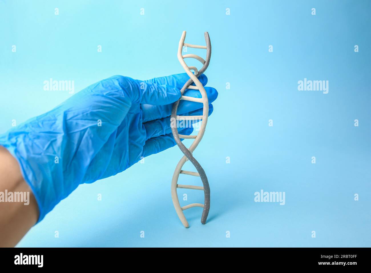 Scientist with DNA molecule model made of plasticine on light blue ...