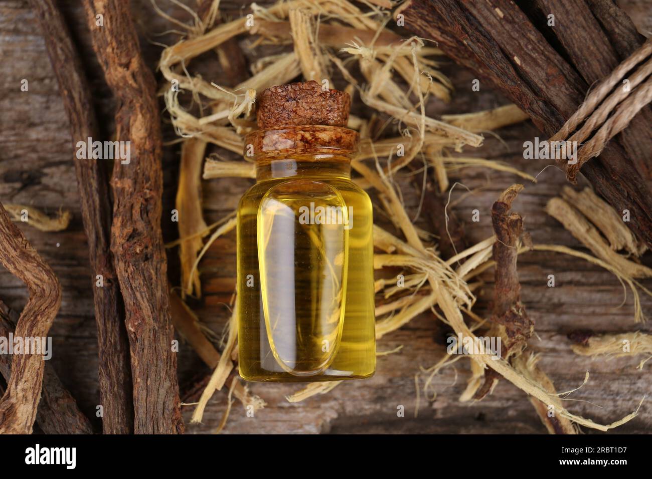 Dried sticks of licorice root and essential oil on wooden table, flat ...