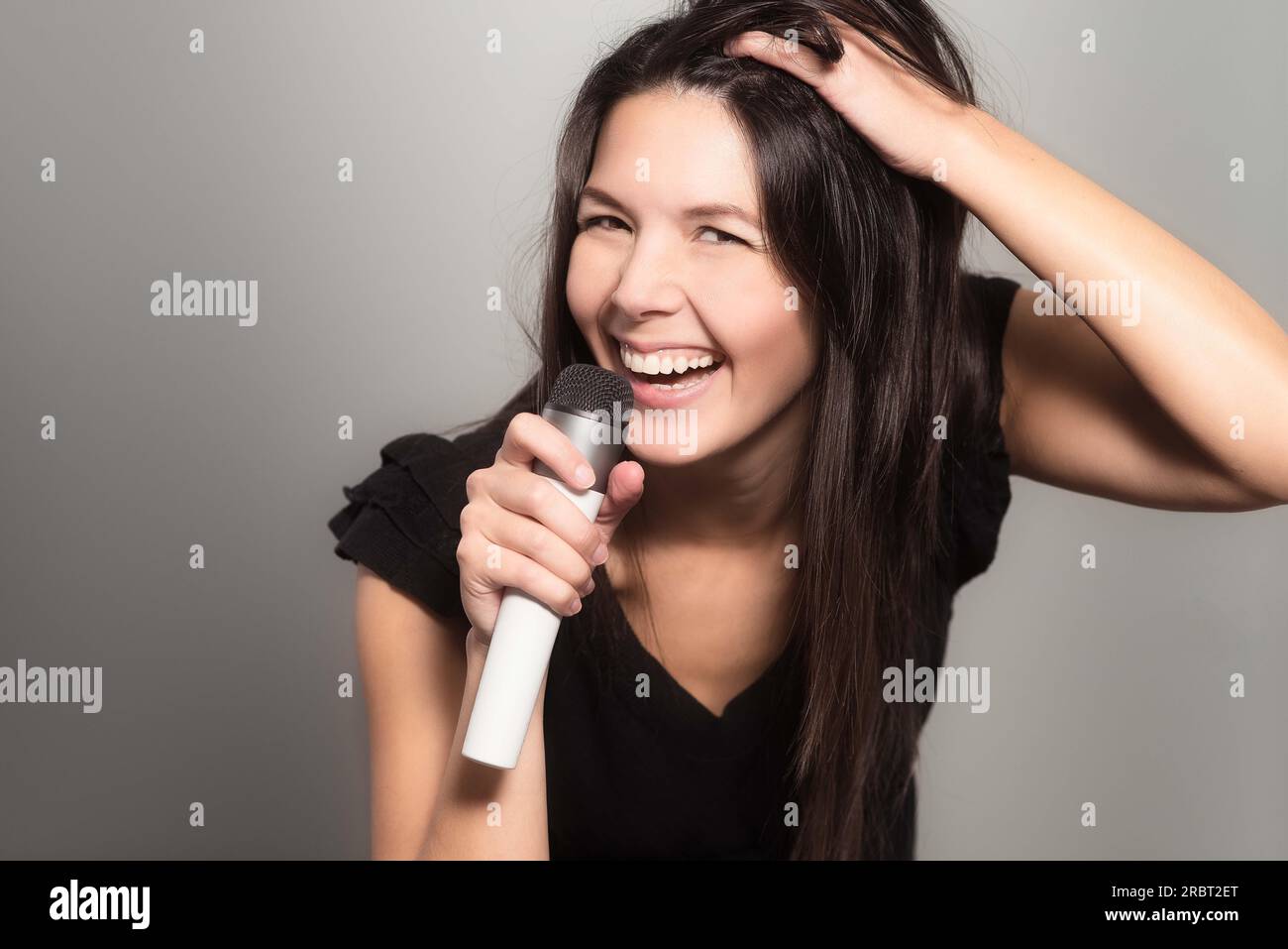 Emotional young woman singing her heart out into a microphone as she ...