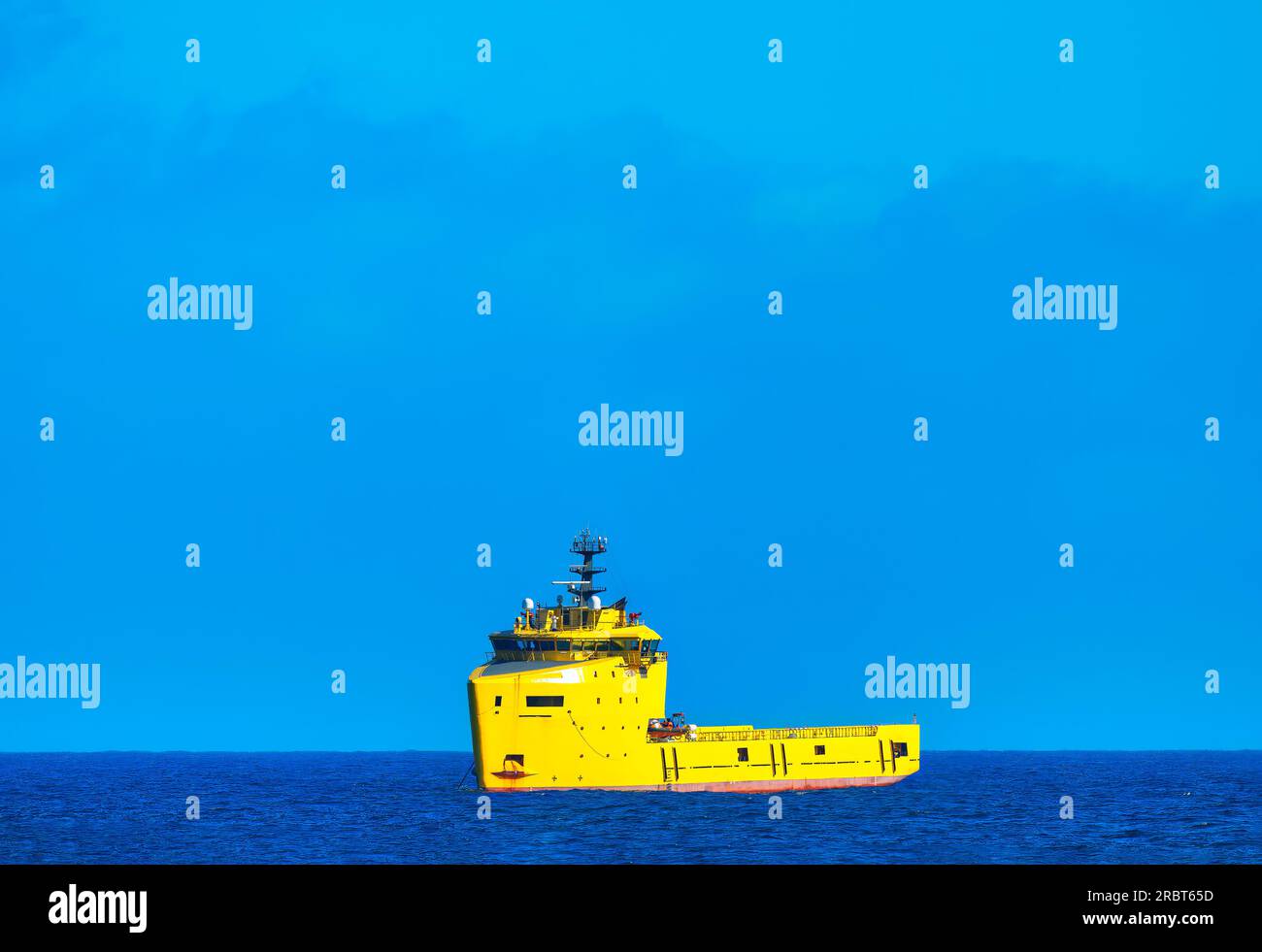 Yellow cargo ship in the sea against the blue sky . Offshore Tug ...