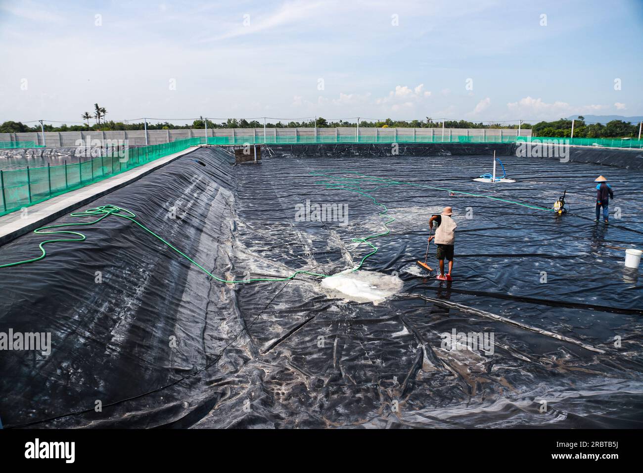 Several pond farmers are cleaning LDPE plastic ponds before starting to ...